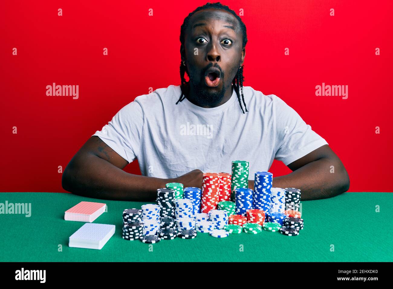 Handsome young black man sitting on the table with poker chips and ...