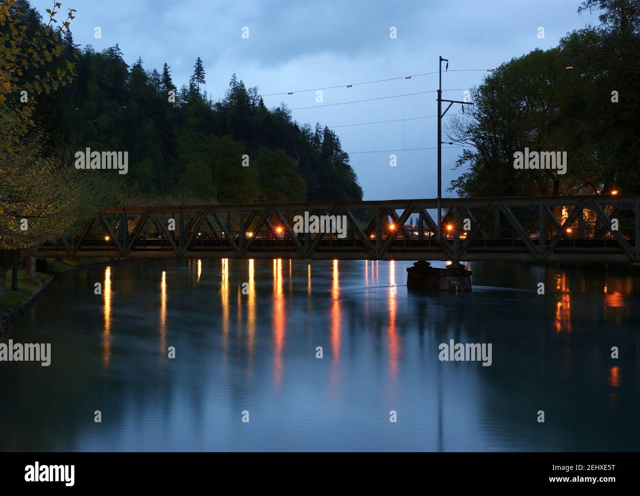 Switzerland, Interlaken. Evening view of a small river and the railroad ...