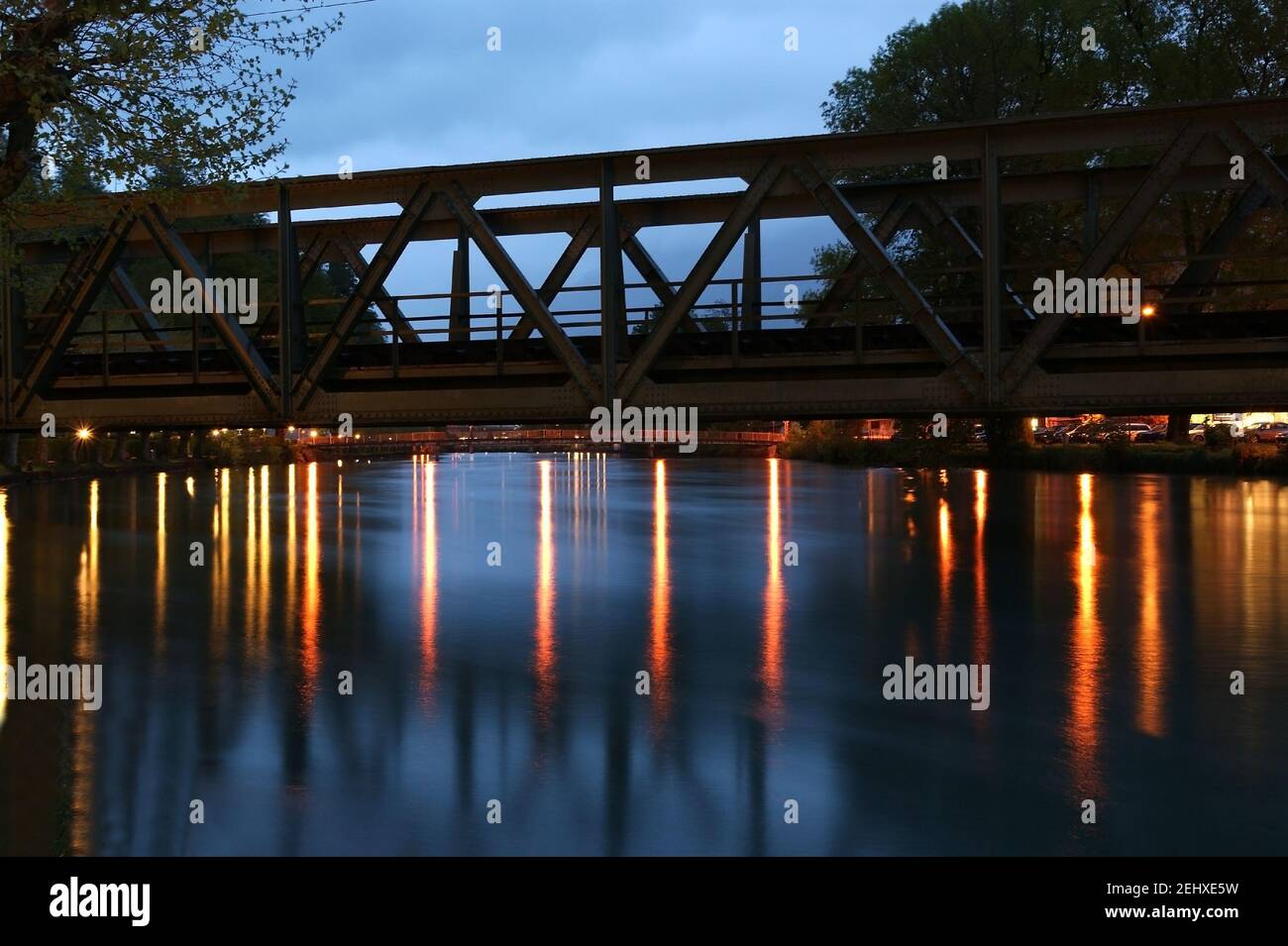 Switzerland, Interlaken. Evening view of a small river and the railroad ...