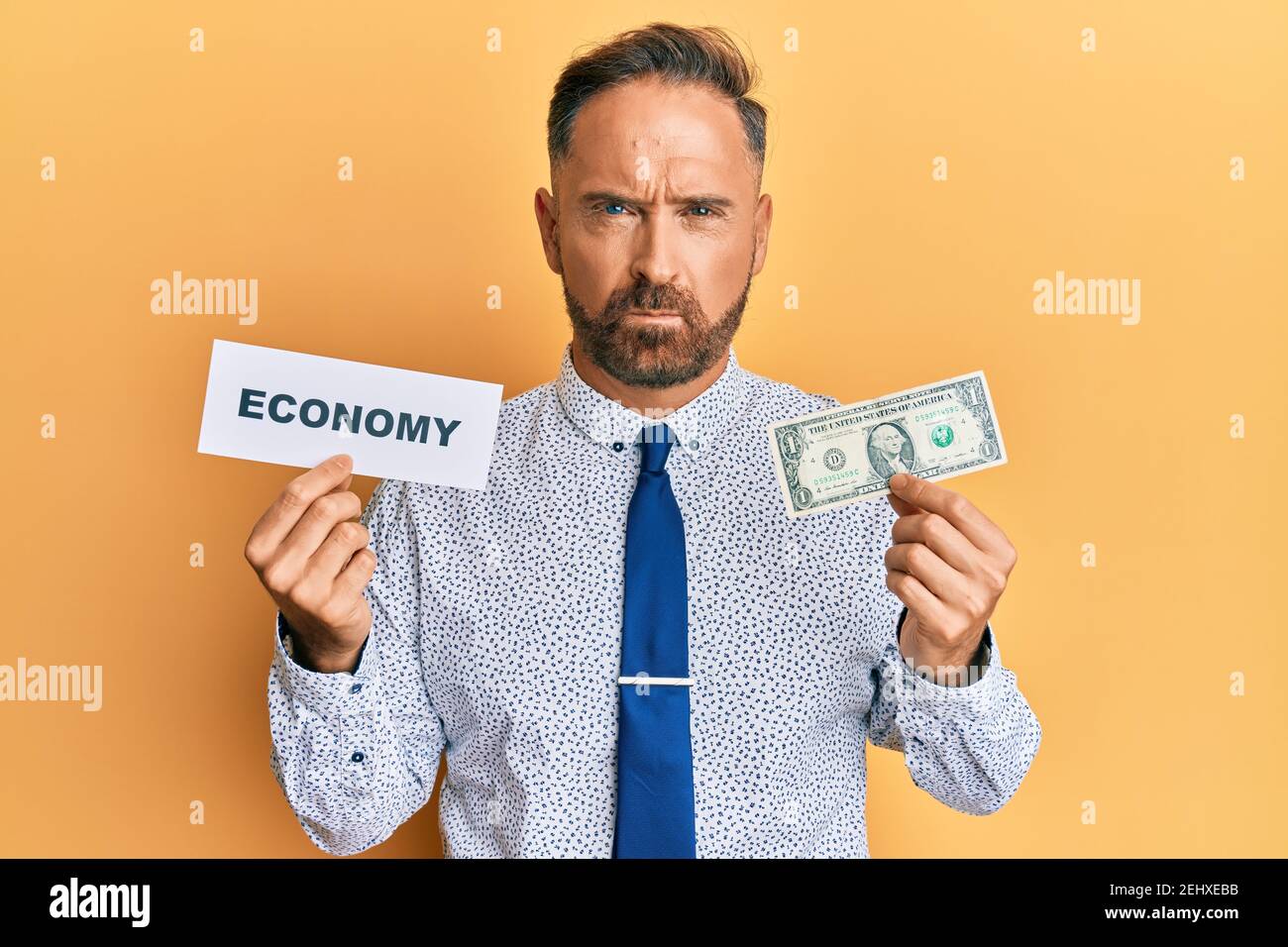 Handsome middle age man holding economy message and holding 1 dollar ...