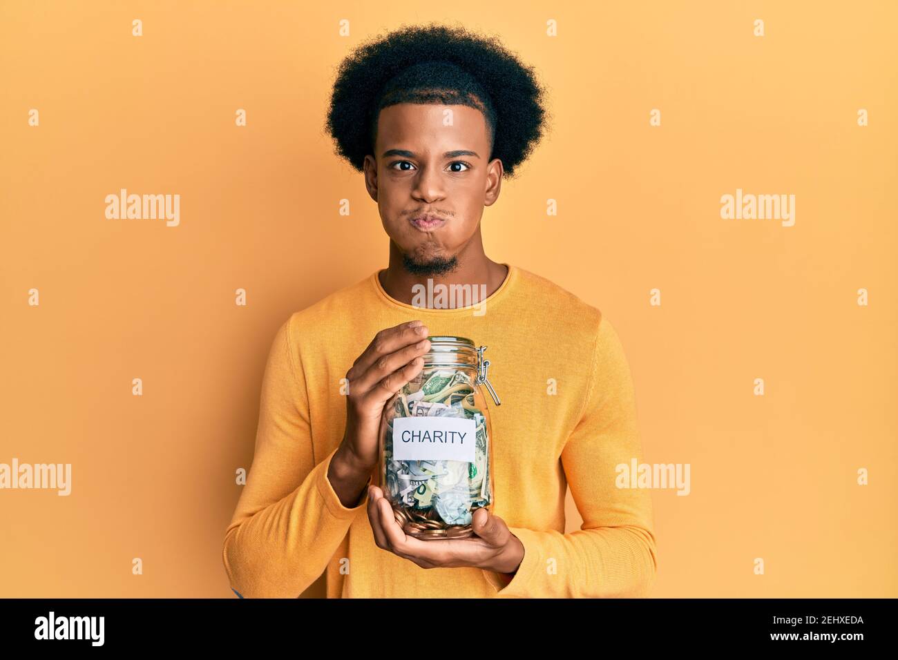 African american man with afro hair holding charity jar with money ...