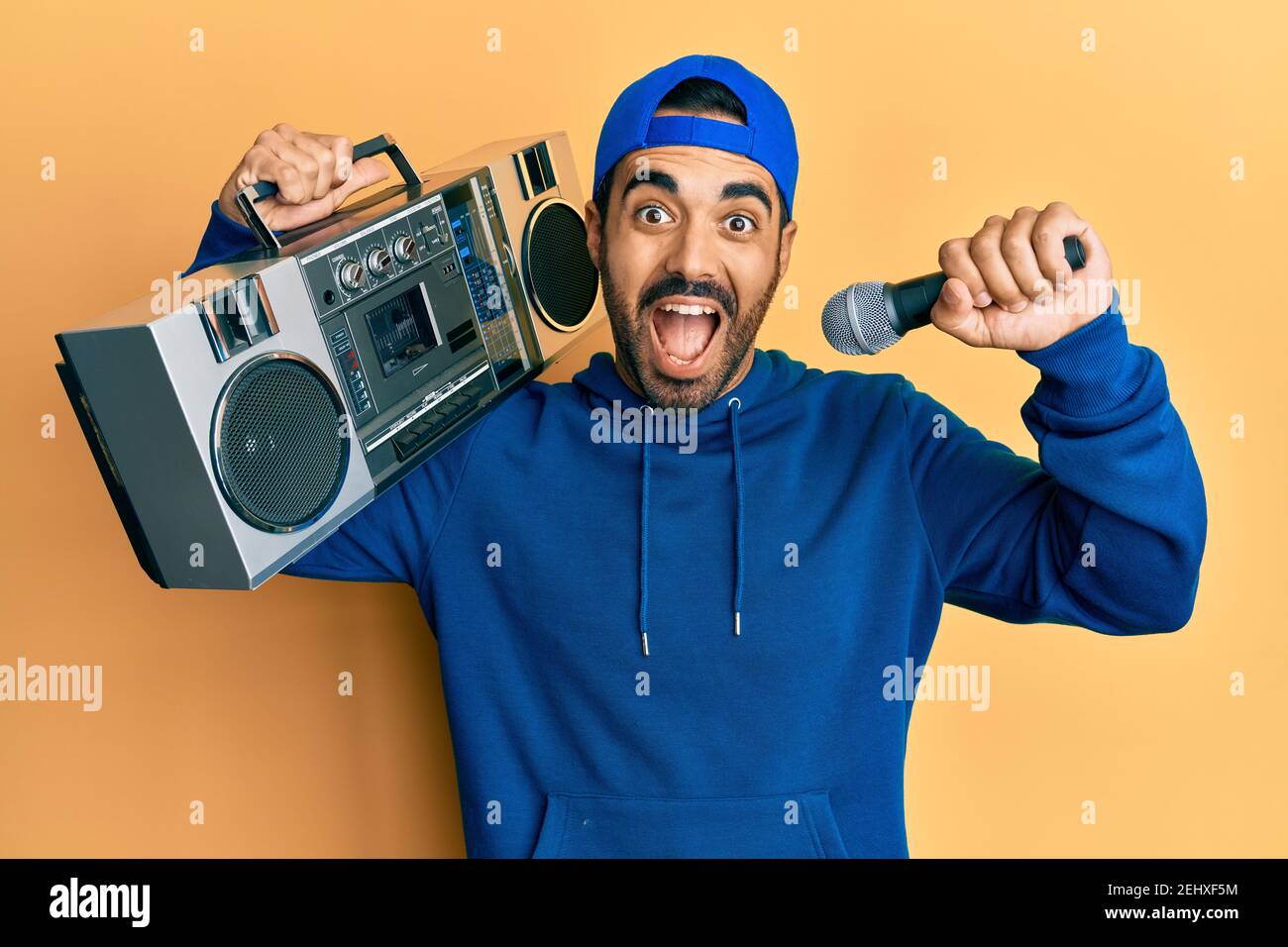 Young hispanic man holding boombox, listening to music singing with ...