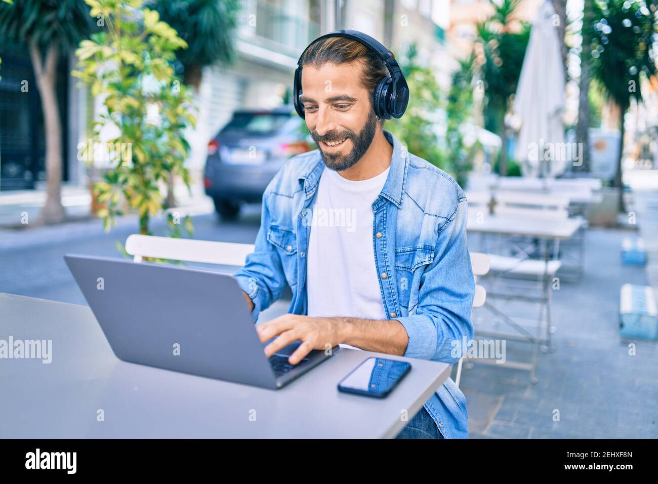 Young middle eastern man working using laptop and headphones at coffee ...