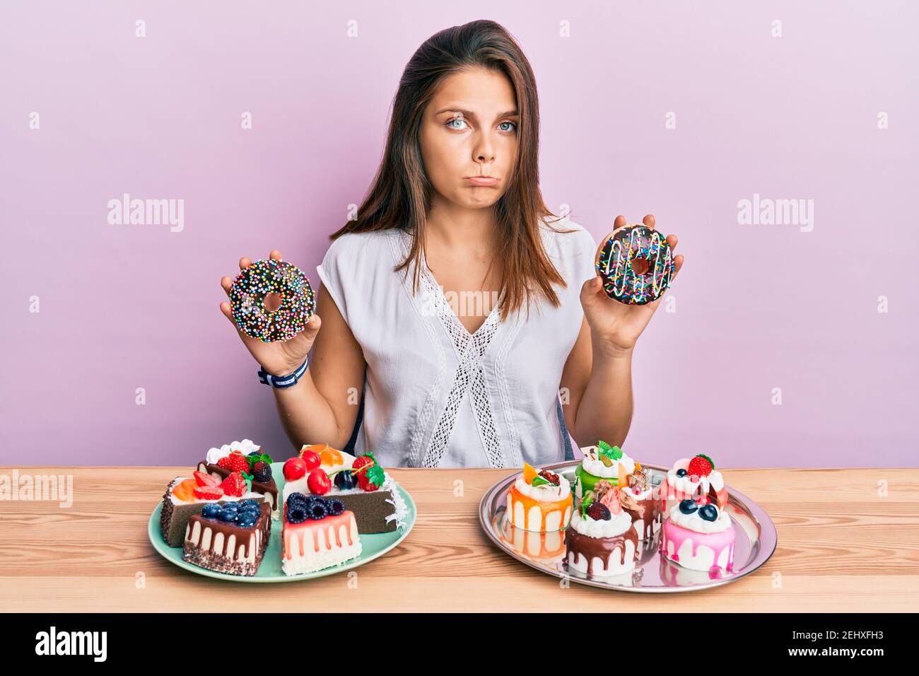 Young caucasian woman eating pastries for breakfast depressed and worry ...