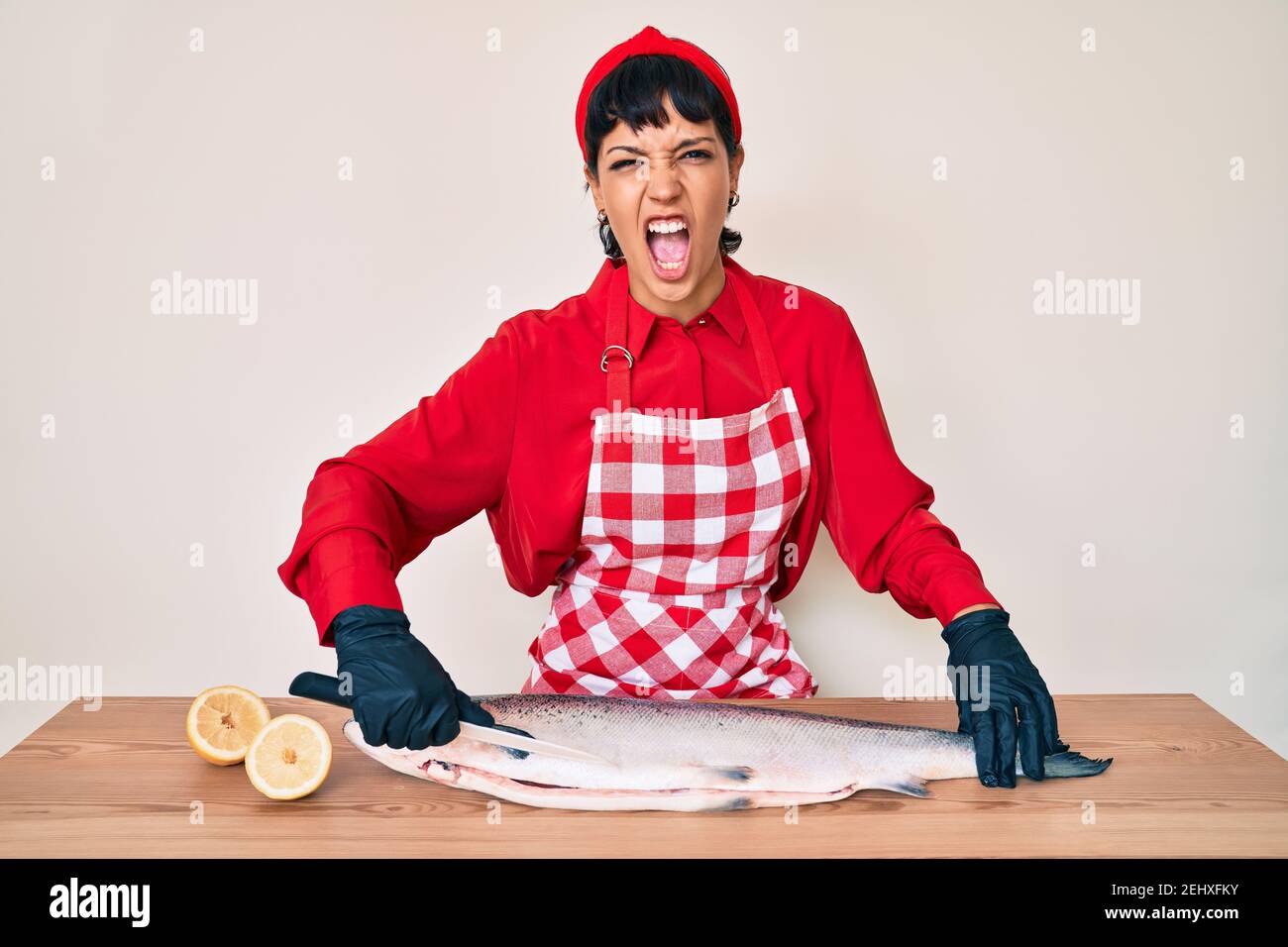 Beautiful brunettte woman fishmonger selling fresh raw salmon angry and ...