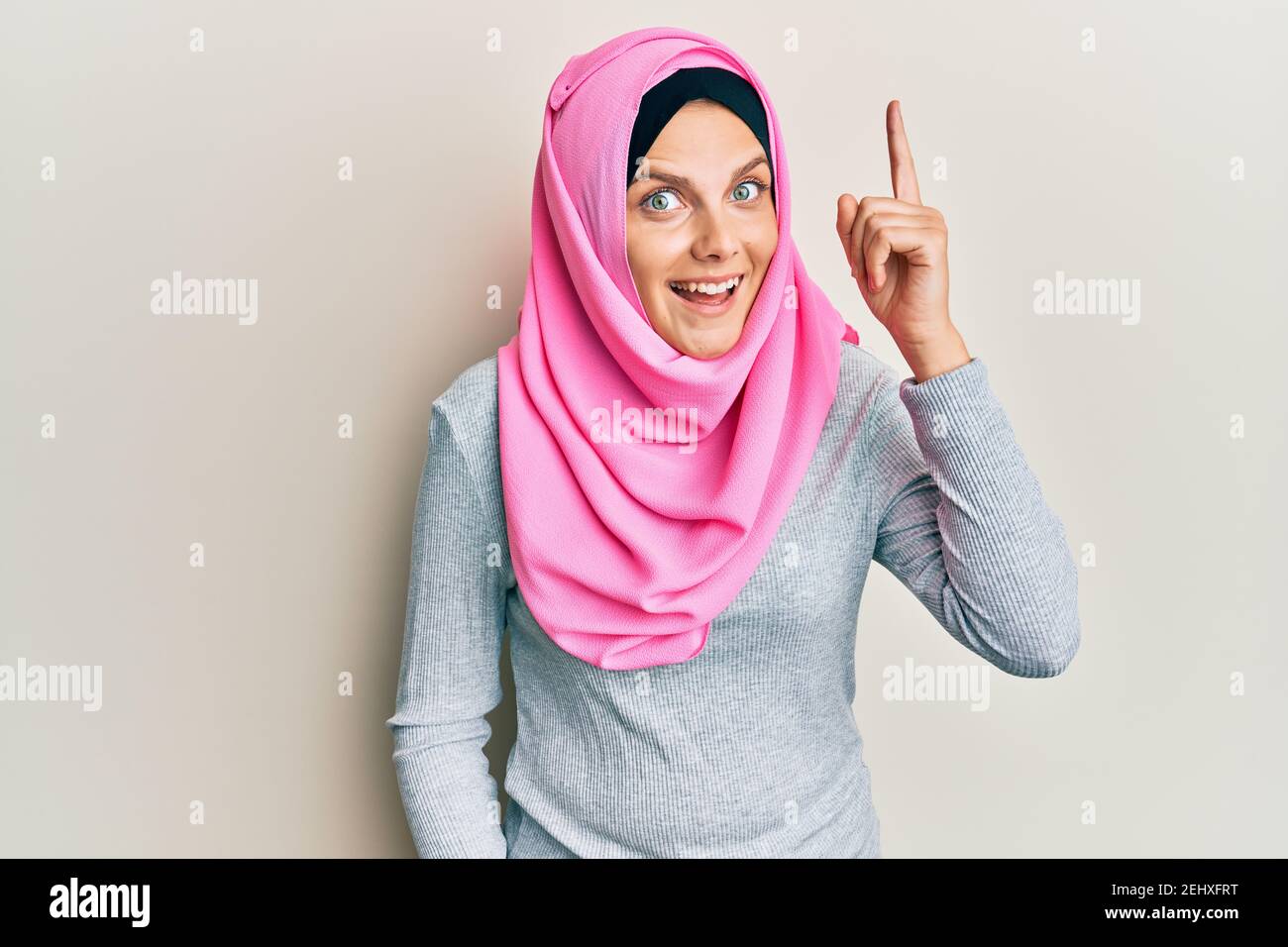Young caucasian woman wearing traditional islamic hijab scarf pointing ...