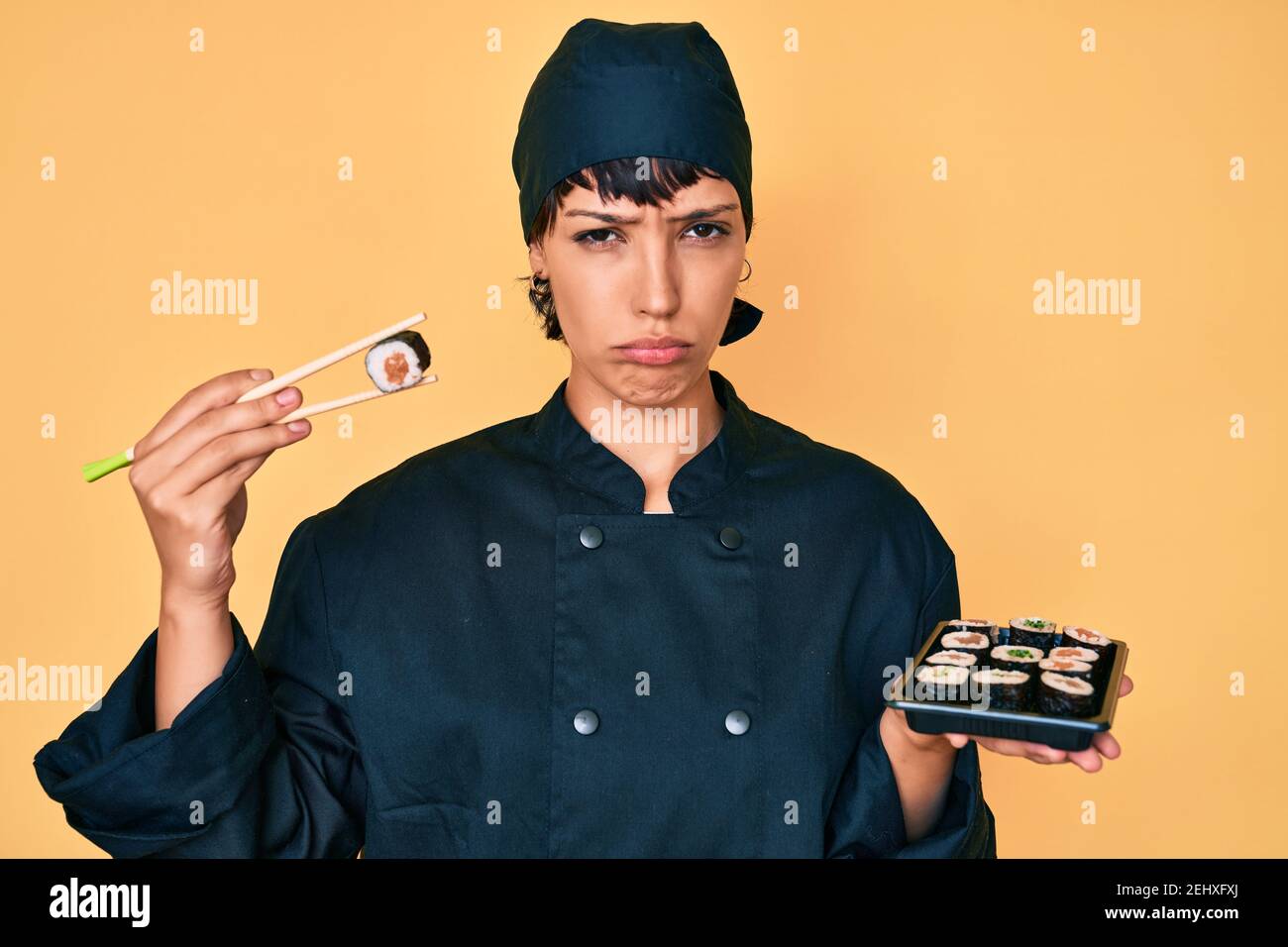 Beautiful brunettte woman chef holding sushi using chopsticks depressed ...