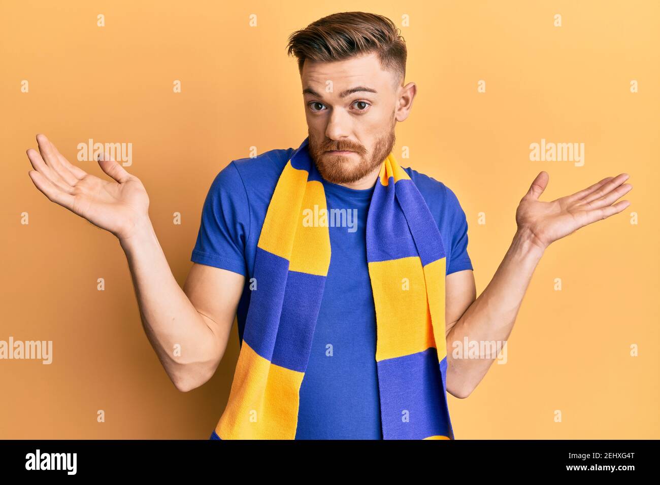 Young redhead man football hooligan cheering game clueless and confused ...