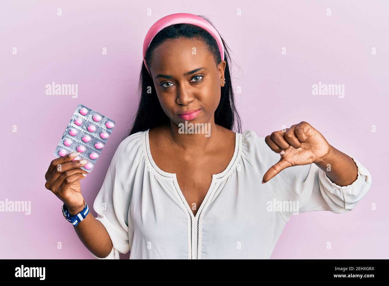 Young african woman holding pills with angry face, negative sign ...