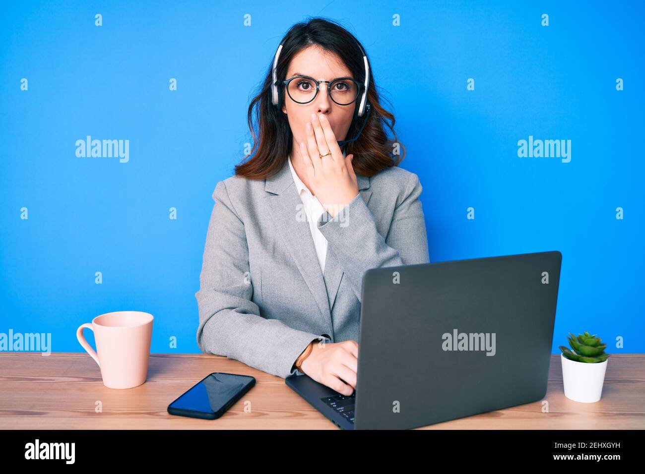 Young beautiful brunette woman working at the office wearing operator ...
