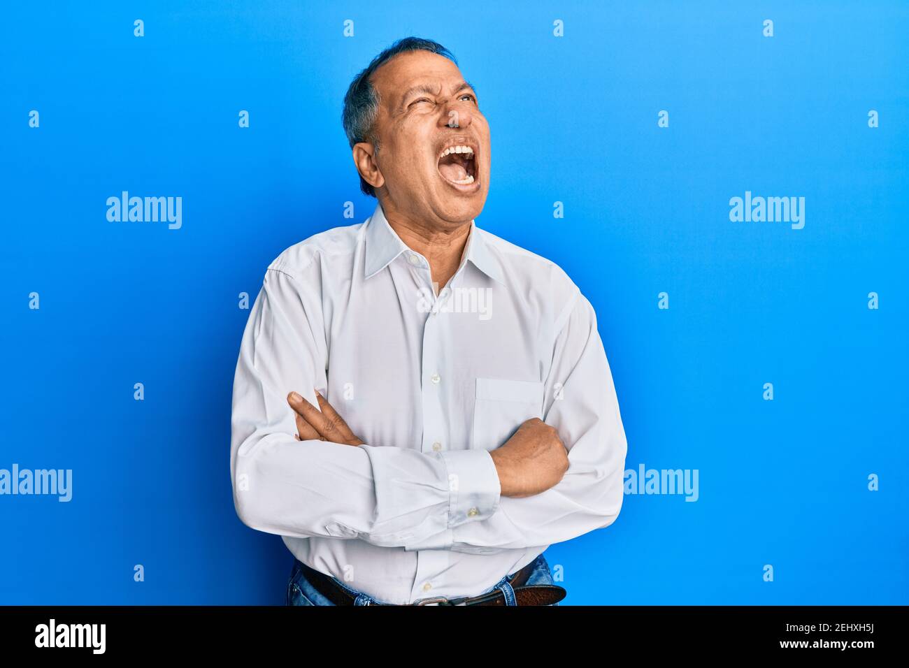 Middle age indian man with arms crossed gesture angry and mad screaming ...