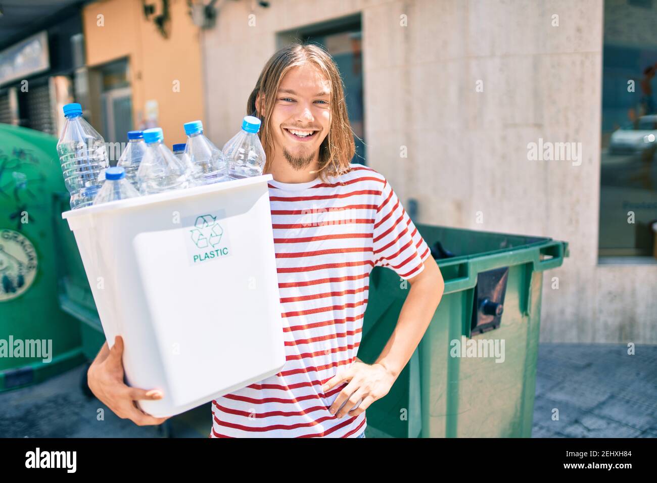 Young caucasian man with blond long hair and beard recycling plastic ...
