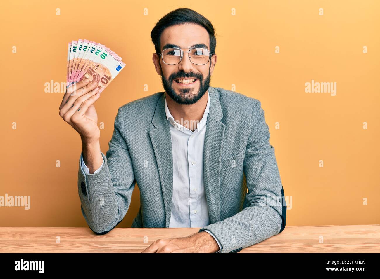 Young hispanic man holding euro banknotes looking positive and happy ...