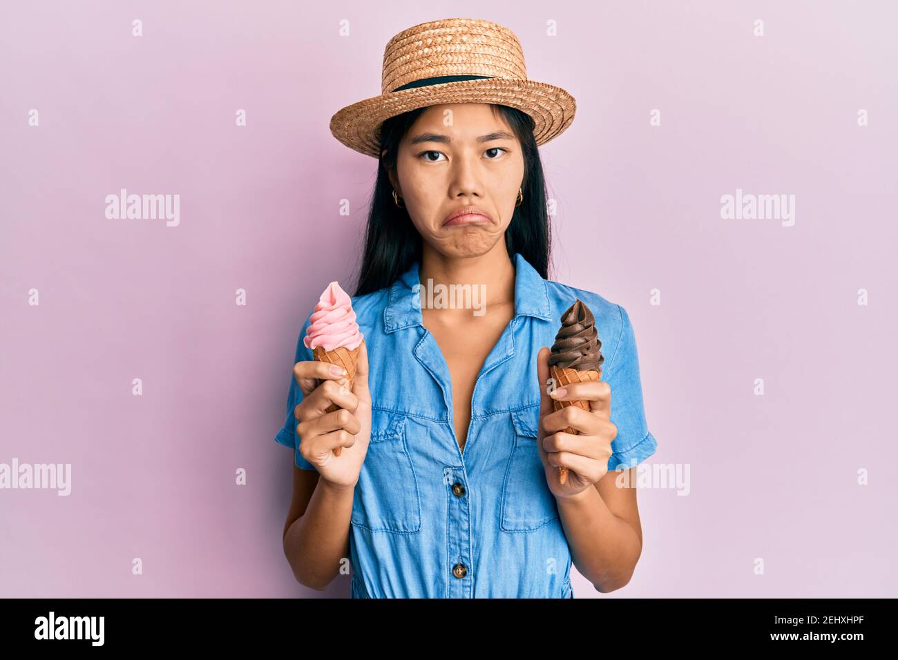 Young chinese woman wearing summer style holding ice cream depressed ...