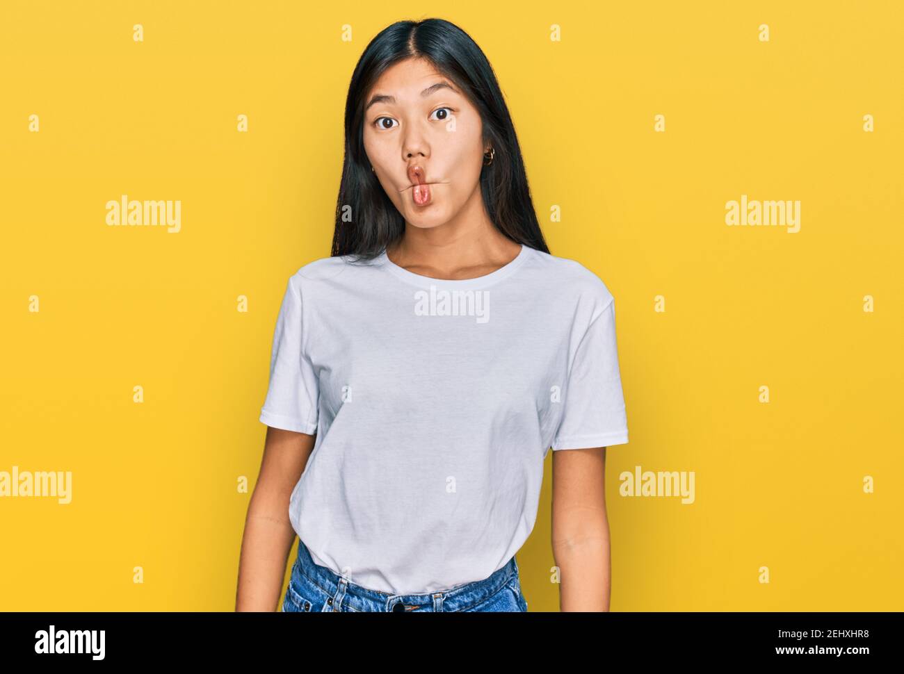 Beautiful young asian woman wearing casual white t shirt making fish ...