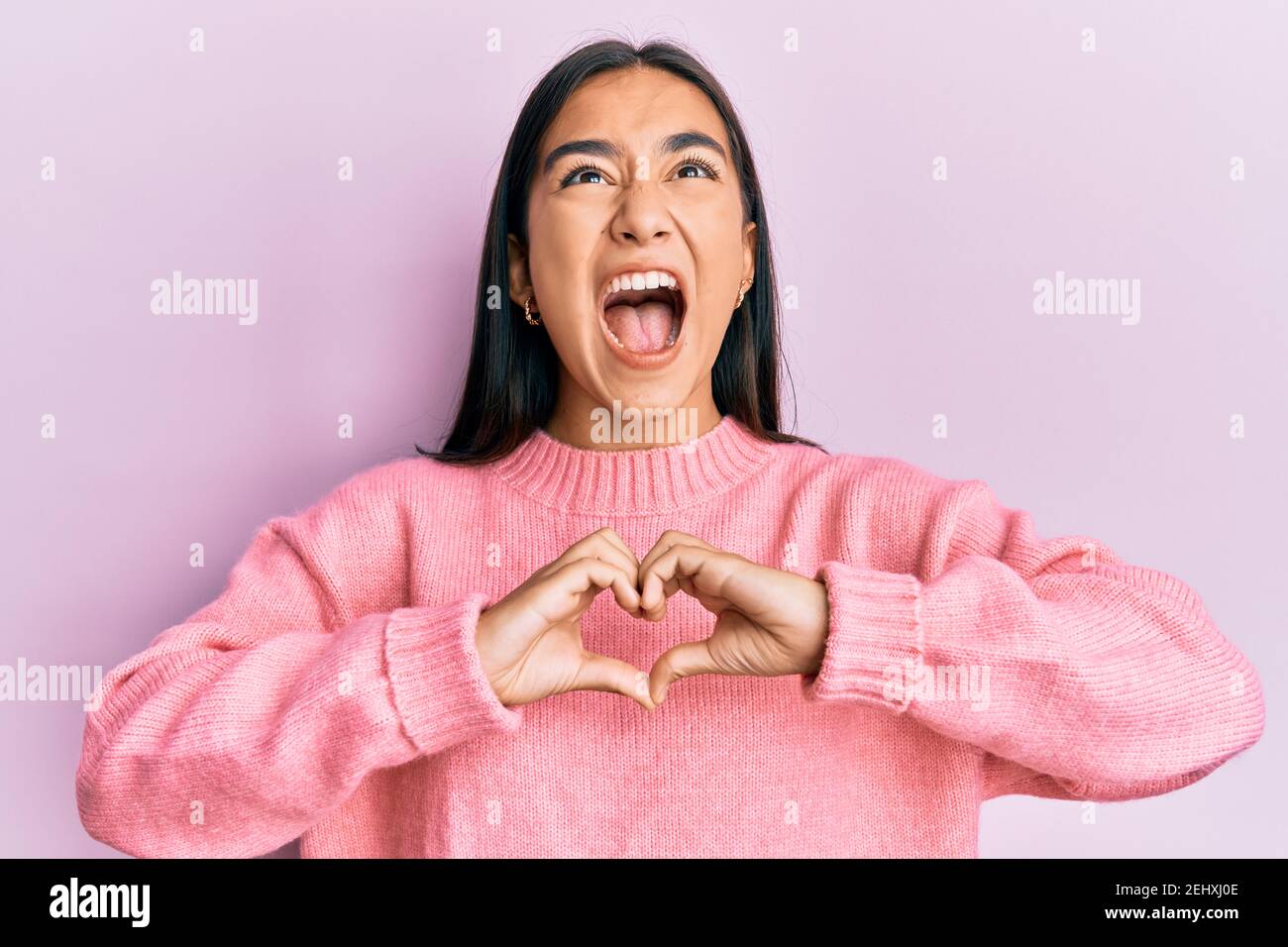 Young asian woman doing heart symbol with hands angry and mad screaming ...