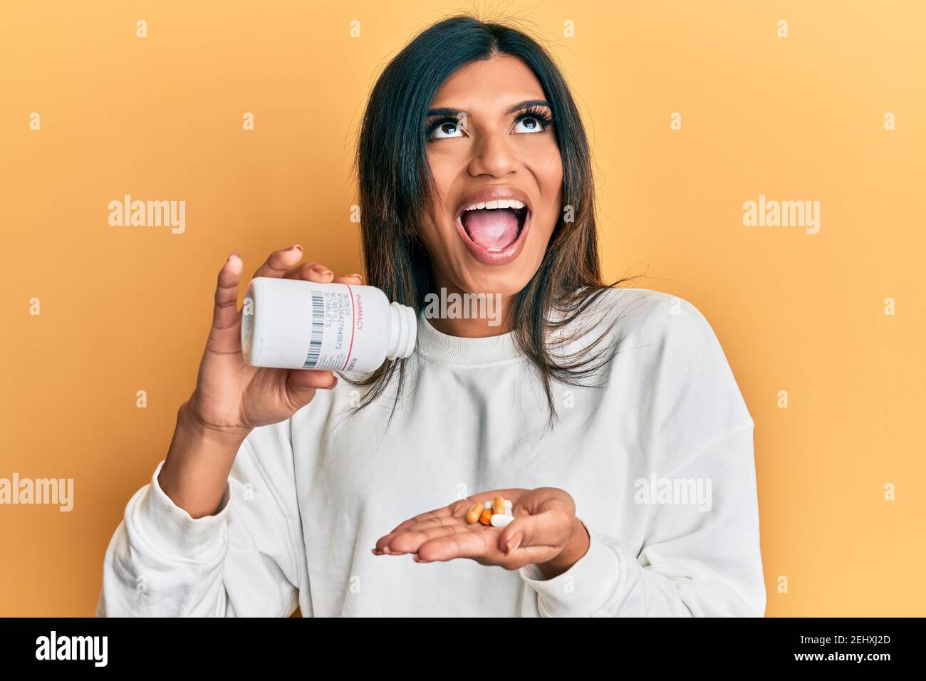 Young latin transsexual transgender woman holding pills angry and mad ...