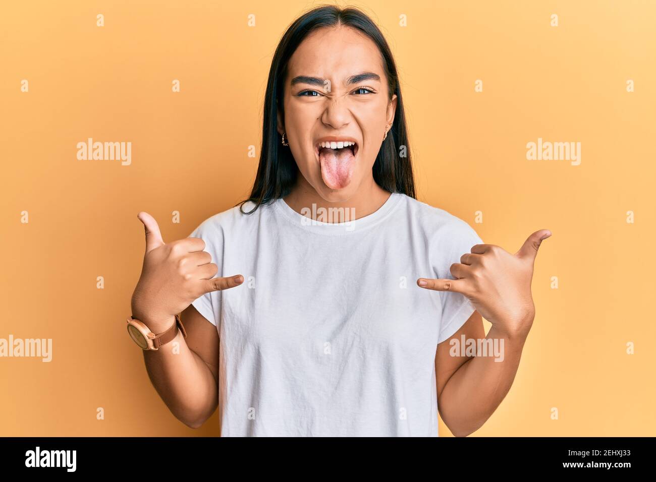 Young asian woman doing shaka sign with hands sticking tongue out happy ...