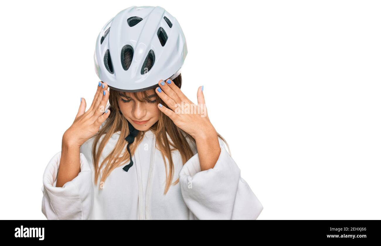 Teenager caucasian girl wearing bike helmet with hand on head for pain ...