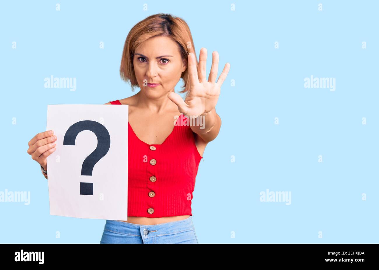 Young blonde woman holding question mark with open hand doing stop sign ...
