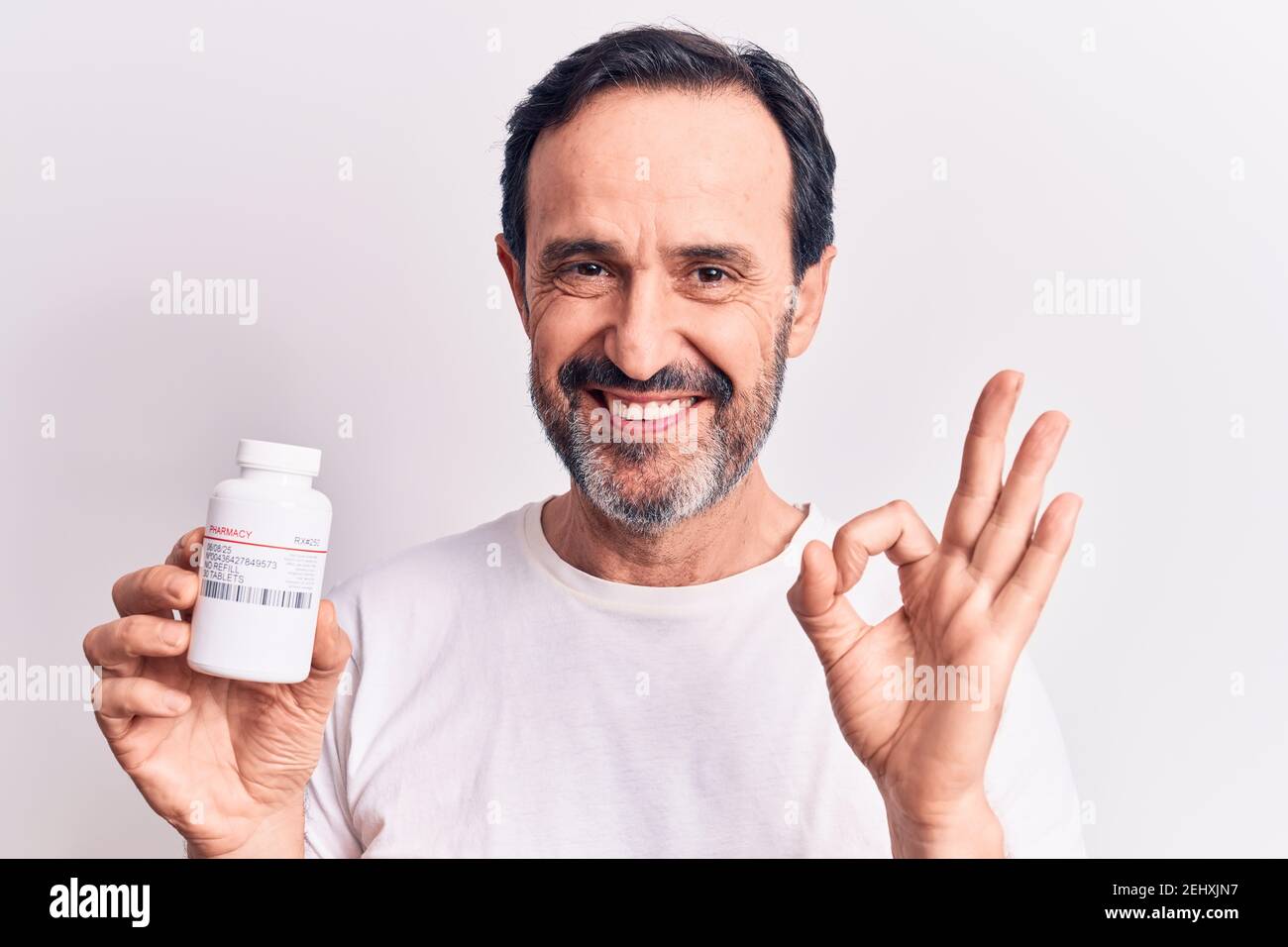 Middle age handsome man holding jar of pills standing over isolated ...