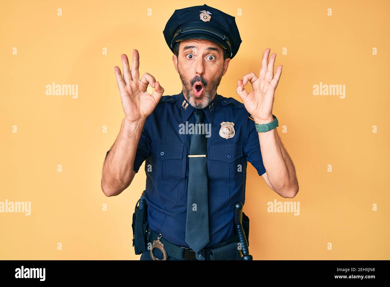 Middle age hispanic man wearing police uniform looking surprised and ...