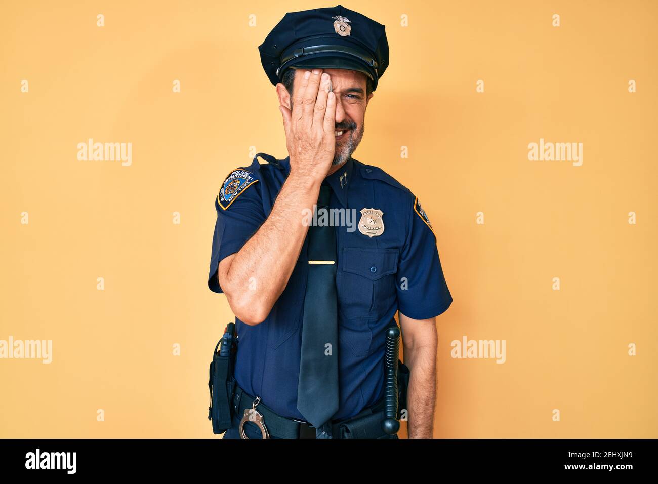 Middle age hispanic man wearing police uniform covering one eye with ...