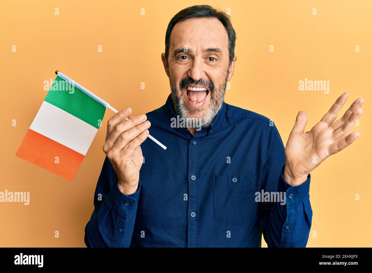 Middle age hispanic man holding ireland flag celebrating achievement ...