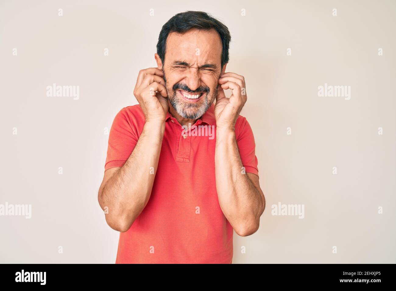 Middle age hispanic man wearing casual clothes covering ears with ...