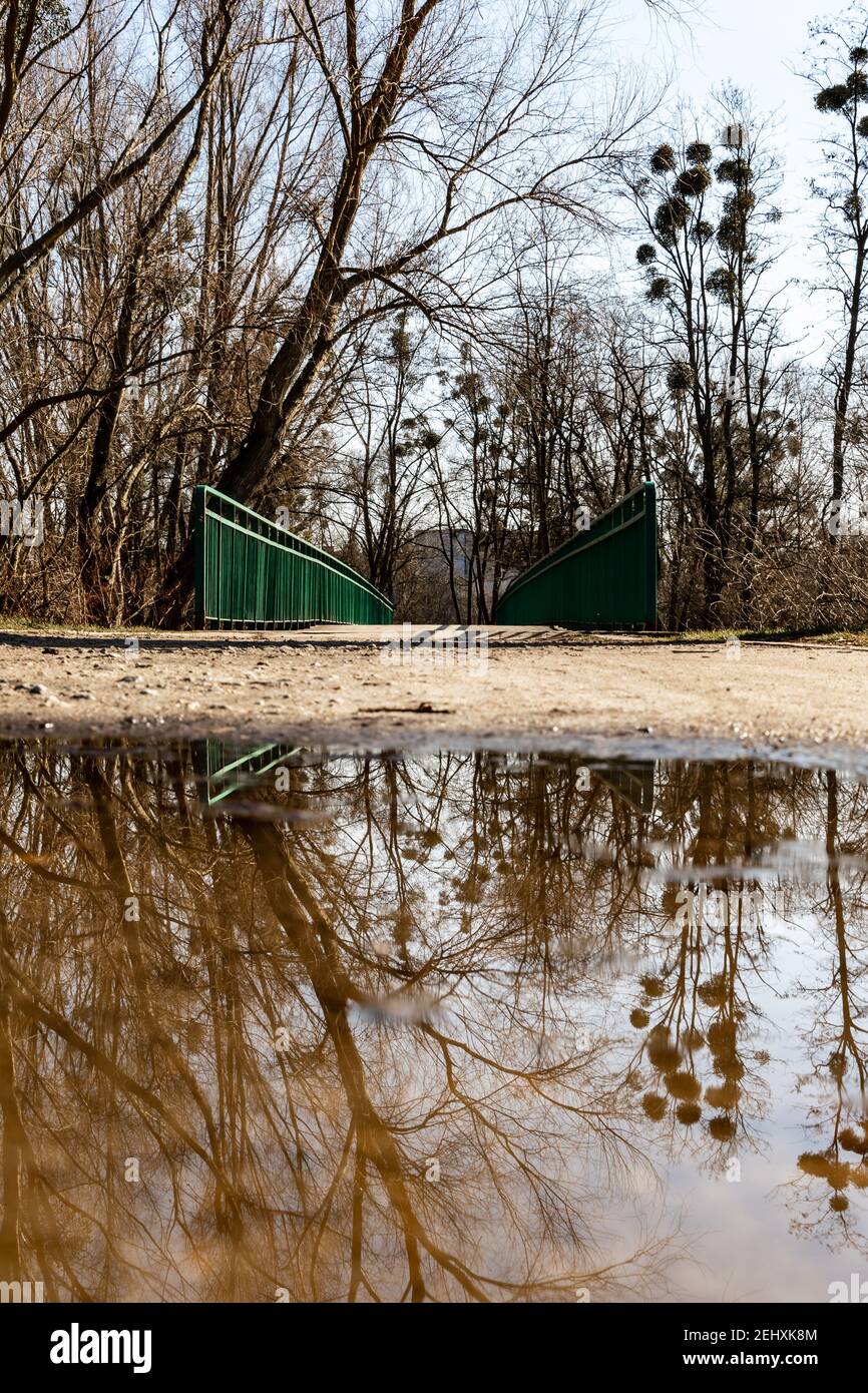 Long concrete bridge over river with green metal railing reflected in ...