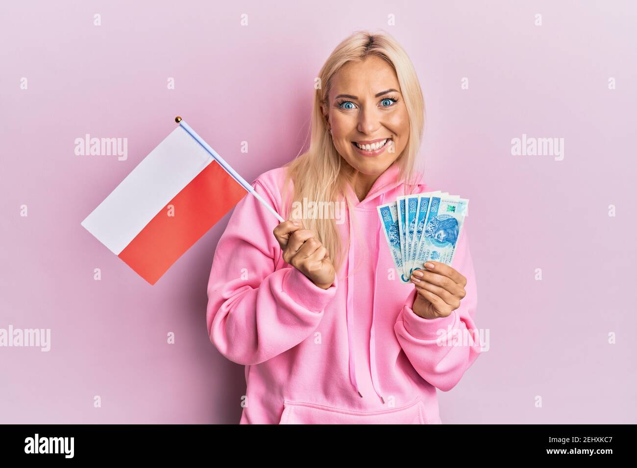 Young blonde woman holding poland flag and zloty banknotes celebrating ...