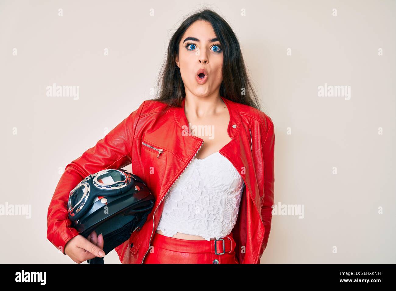Brunette teenager girl wearing bike helmet scared and amazed with open ...