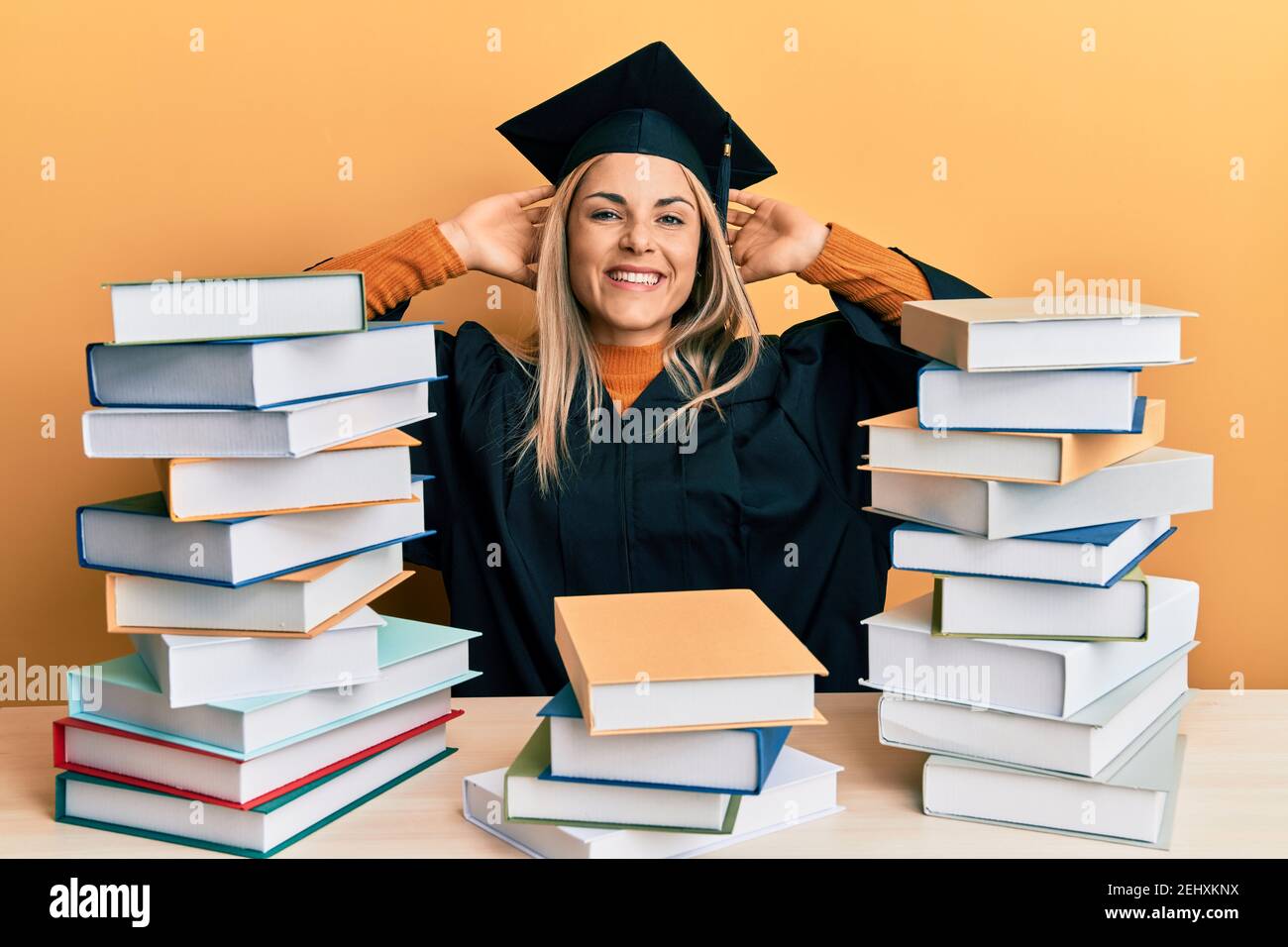 Young caucasian woman wearing graduation ceremony robe sitting on the ...