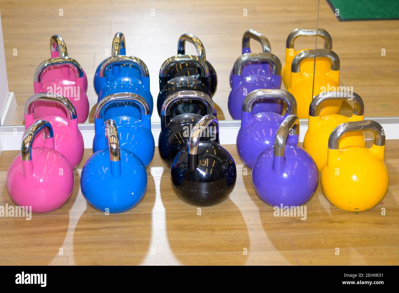 Set of brightly colored kettle weights on the wooden floor in a gym in ...