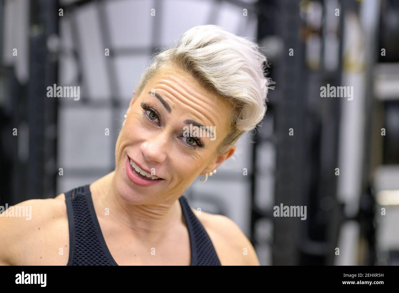 Attractive blond woman with an amused quizzical expression smiling as ...