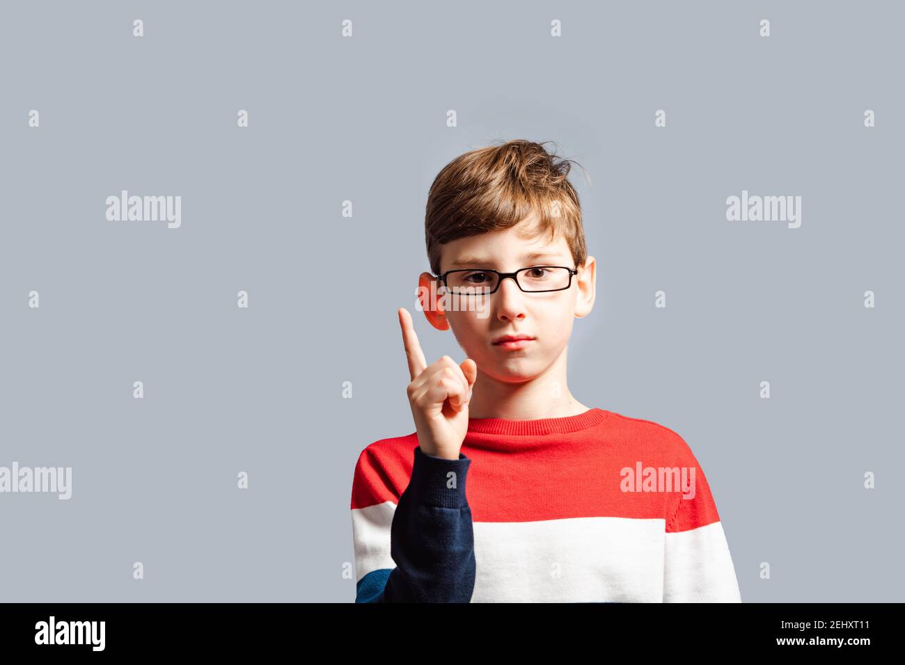 Thoughtful blond hair boy in glasses holding index finger Stock Photo ...