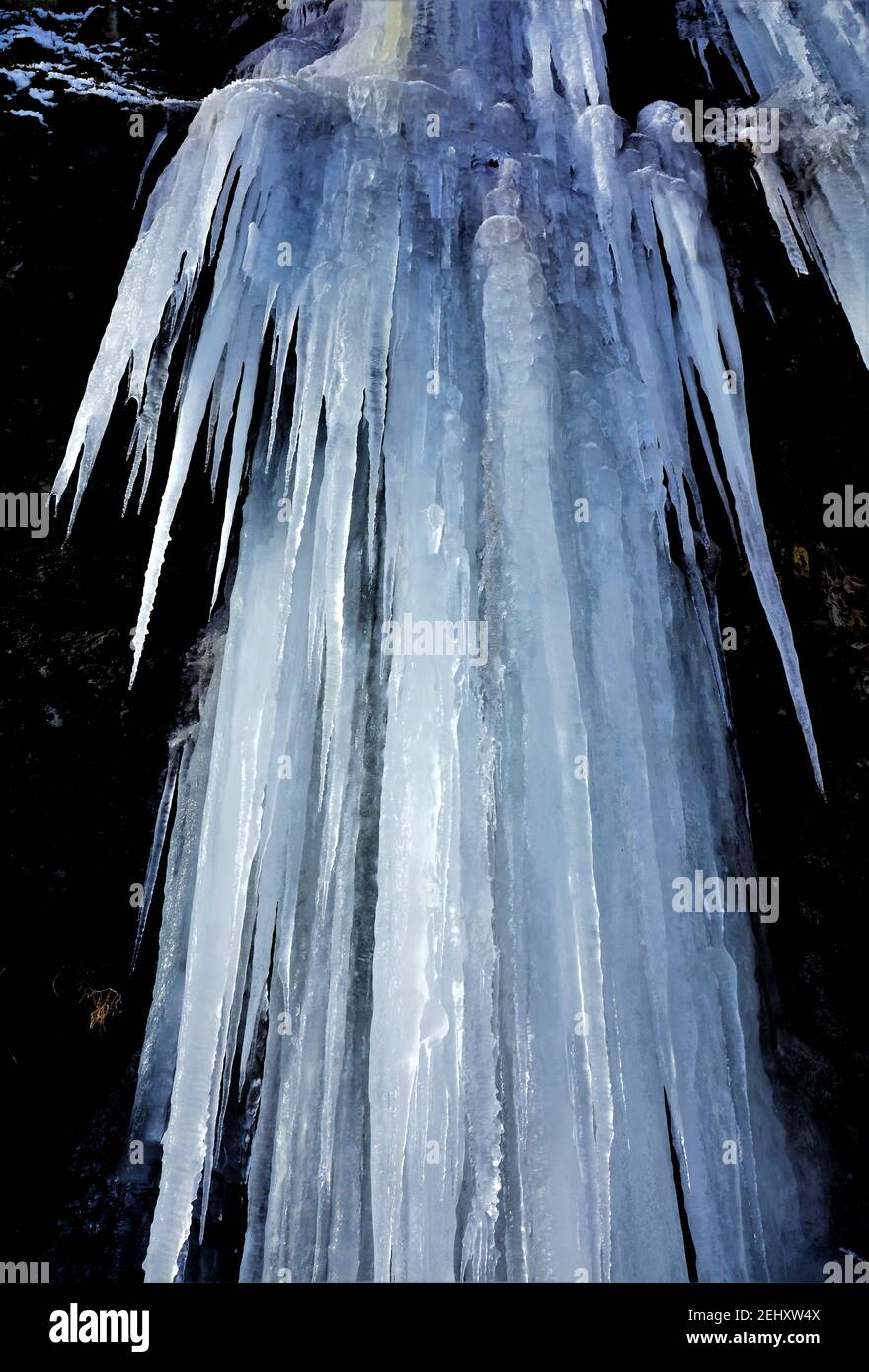 Vertical shot of Tall icicles hanging on a high cliff Stock Photo - Alamy