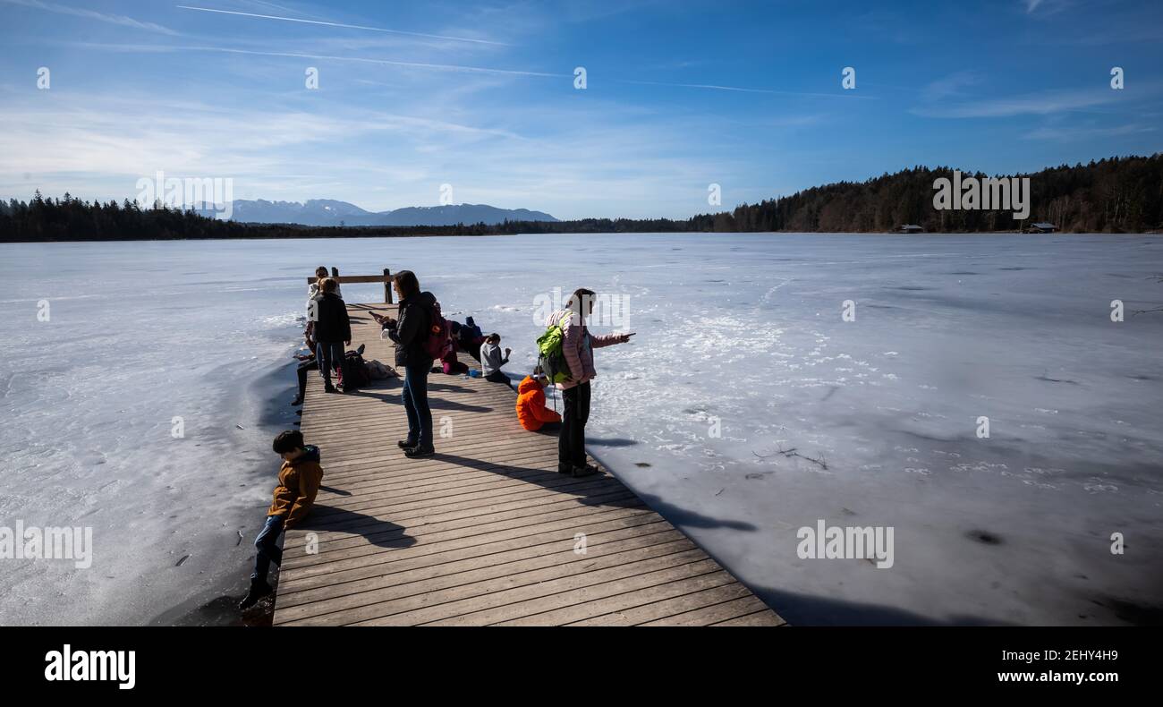 20 February 2021, Bavaria, Sachsenkam: Visitors to the frozen Kirchsee ...