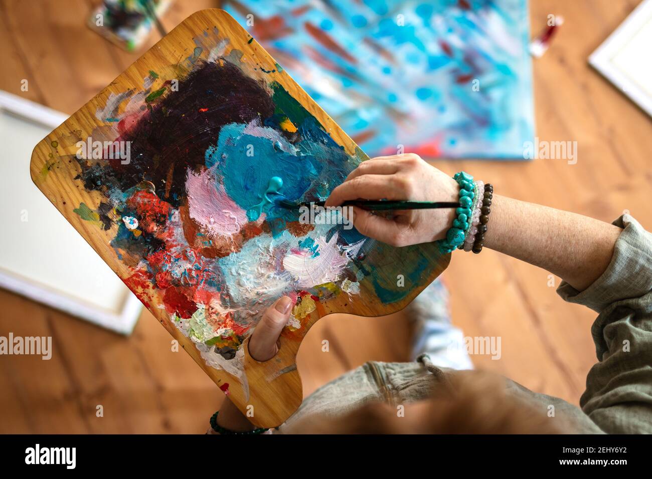 Woman artist mixing acrylic colors at palette and working on paintings ...
