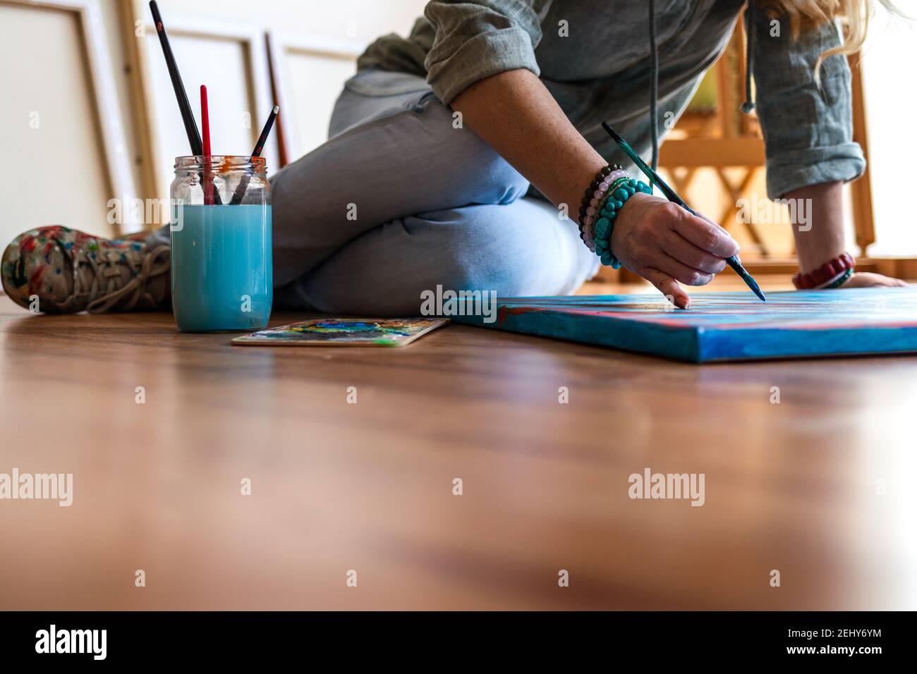 Artist painting modern abstract paintings at studio. Woman sitting on ...