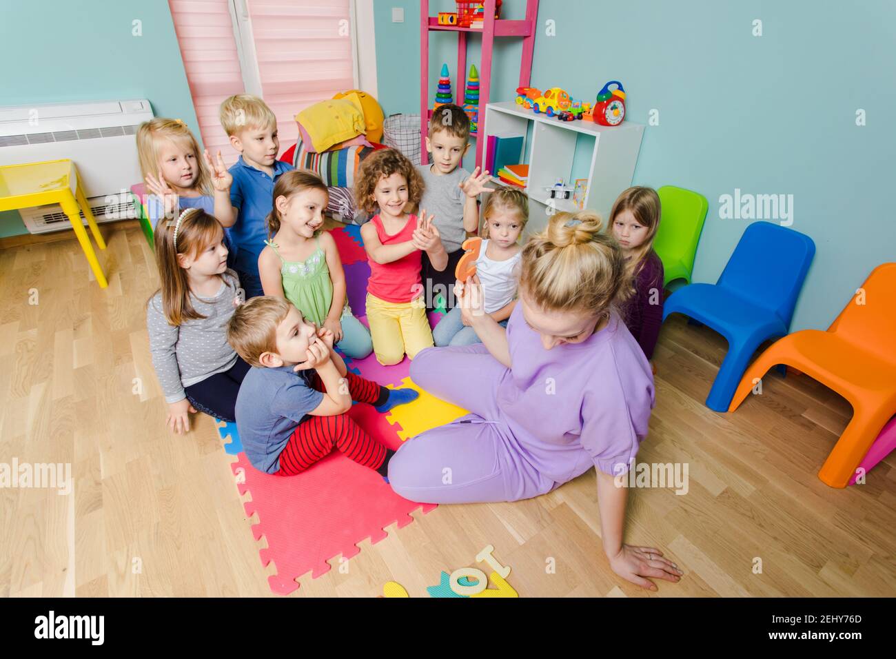 Lovely preschoolers listening young teacher very carefully Stock Photo ...