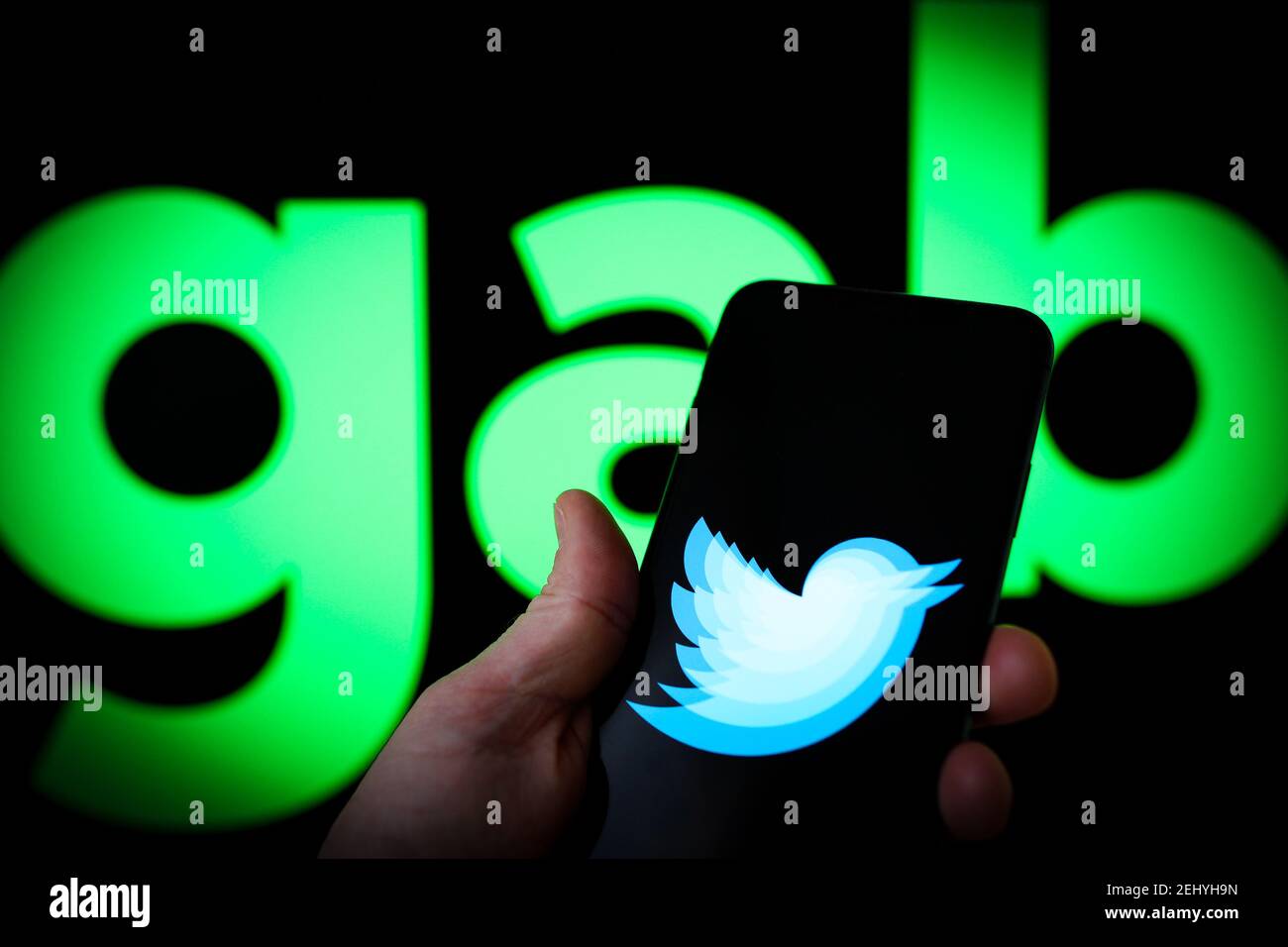 The Twitter logo is seen on a mobile device with the Gab logo in the ...