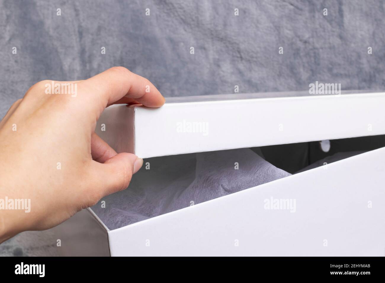 Hand opening cardboard box on a gray background Stock Photo - Alamy