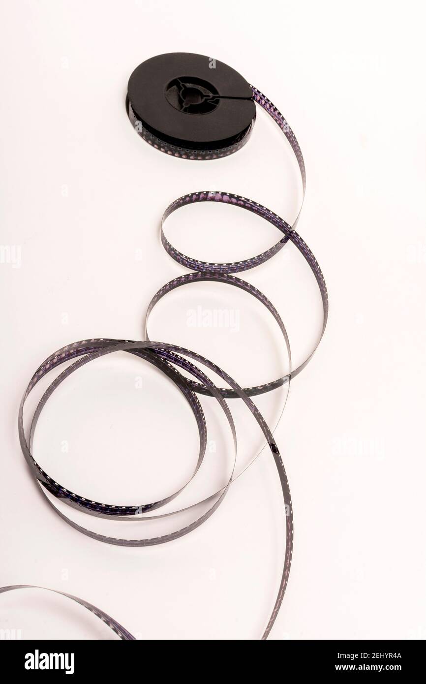 Film reel unwinding on a white surface with creative shadows visible ...