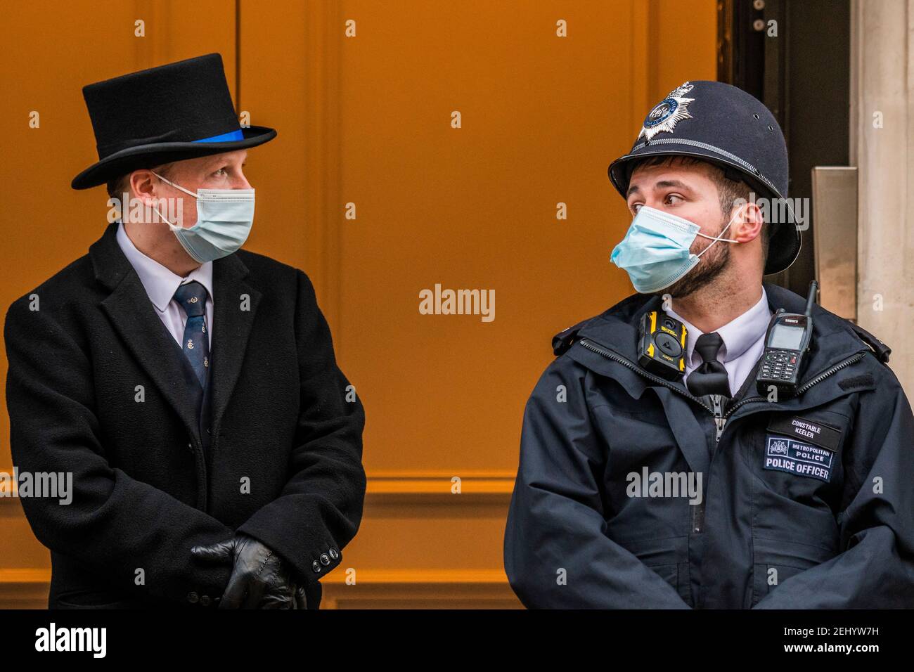 London, UK. 20th Feb, 2021. Police and a doorman in a top hat guard the ...