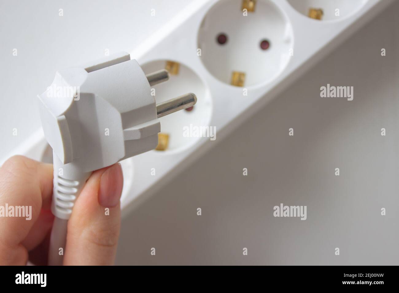 hand holds white plug from white socket on white background Stock Photo ...