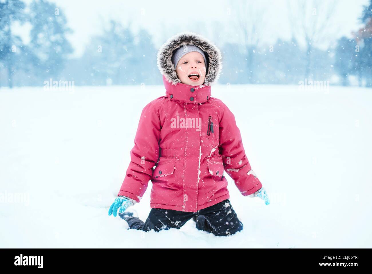 Cute adorable funny Caucasian excited girl child eating licking snow ...