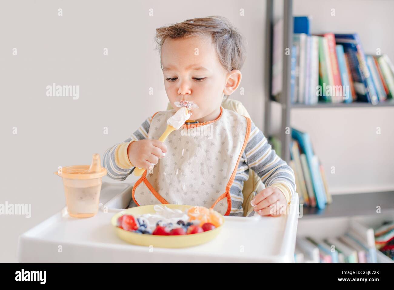 Cute Caucasian baby boy eating ripe berries and fruits with yogurt ...