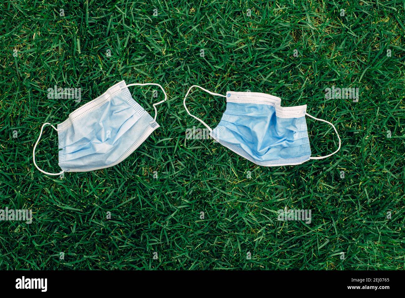 Two used sanitary masks lying on grass ground. Disposable recyclable ...