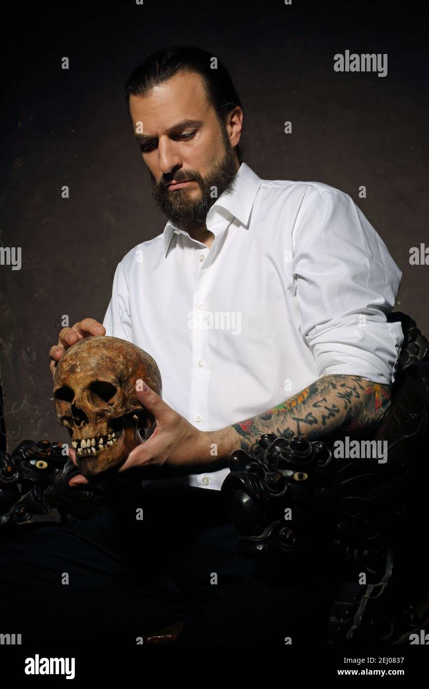 man holding a human skull. man looking at a skull Stock Photo - Alamy